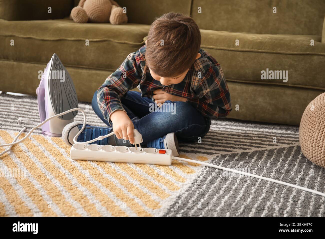 Little boy playing with electric extension cord and iron at home Stock ...