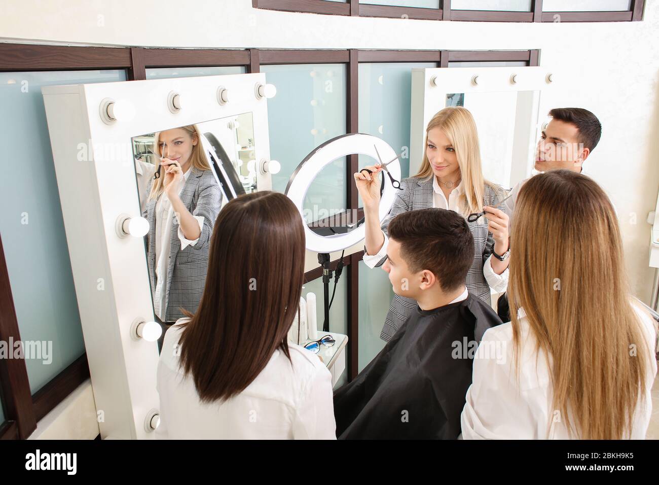 Professional hairdresser teaching young people in salon Stock Photo - Alamy
