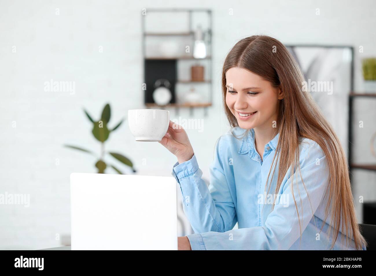 Young woman drinking coffee while working on laptop in cafe Stock Photo ...