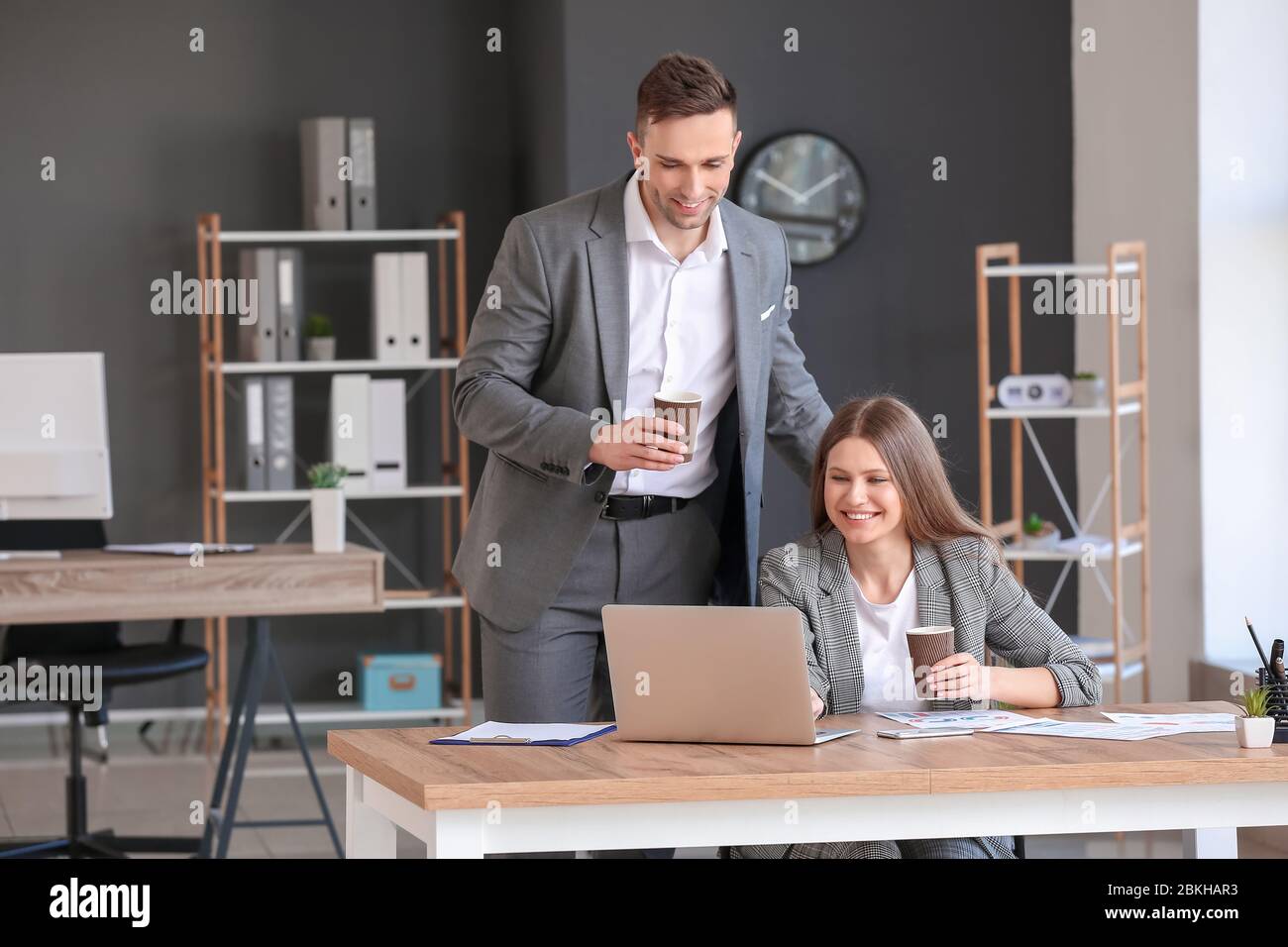 Young colleagues drinking coffee while working in office Stock Photo ...