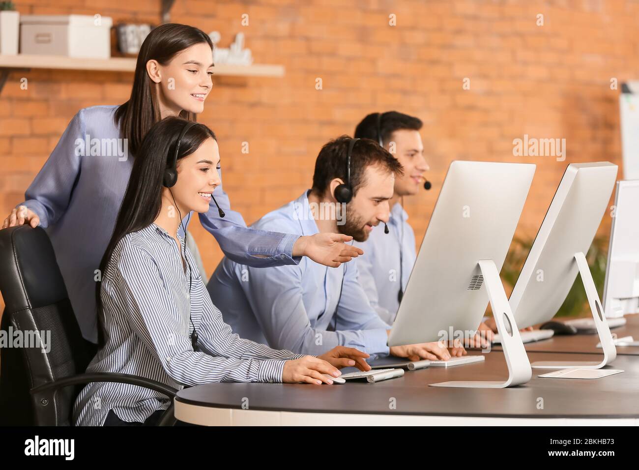 Professional technical support agent teaching young people in office ...