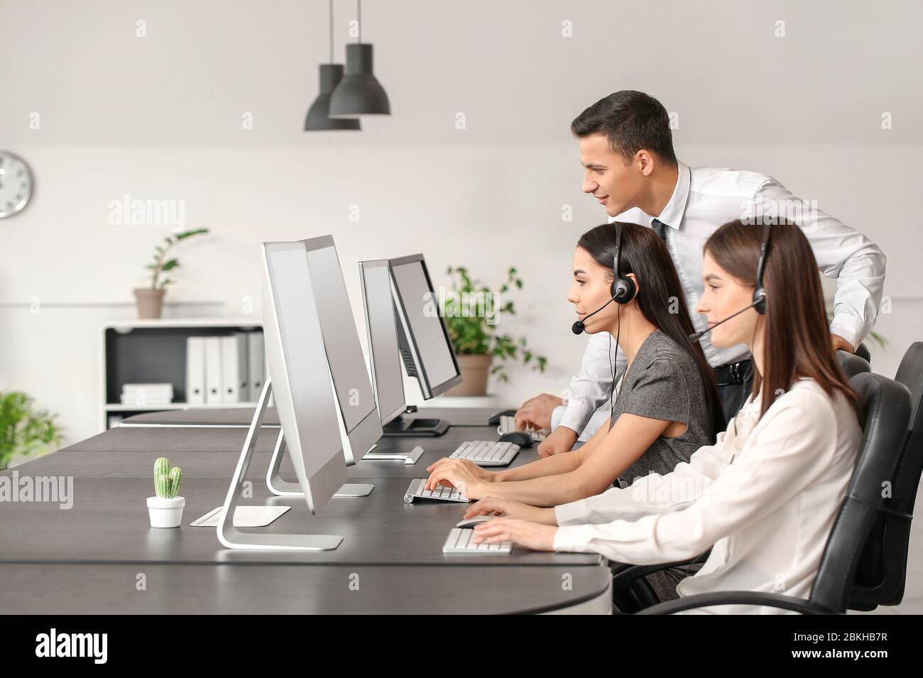 Professional technical support agent teaching young people in office ...