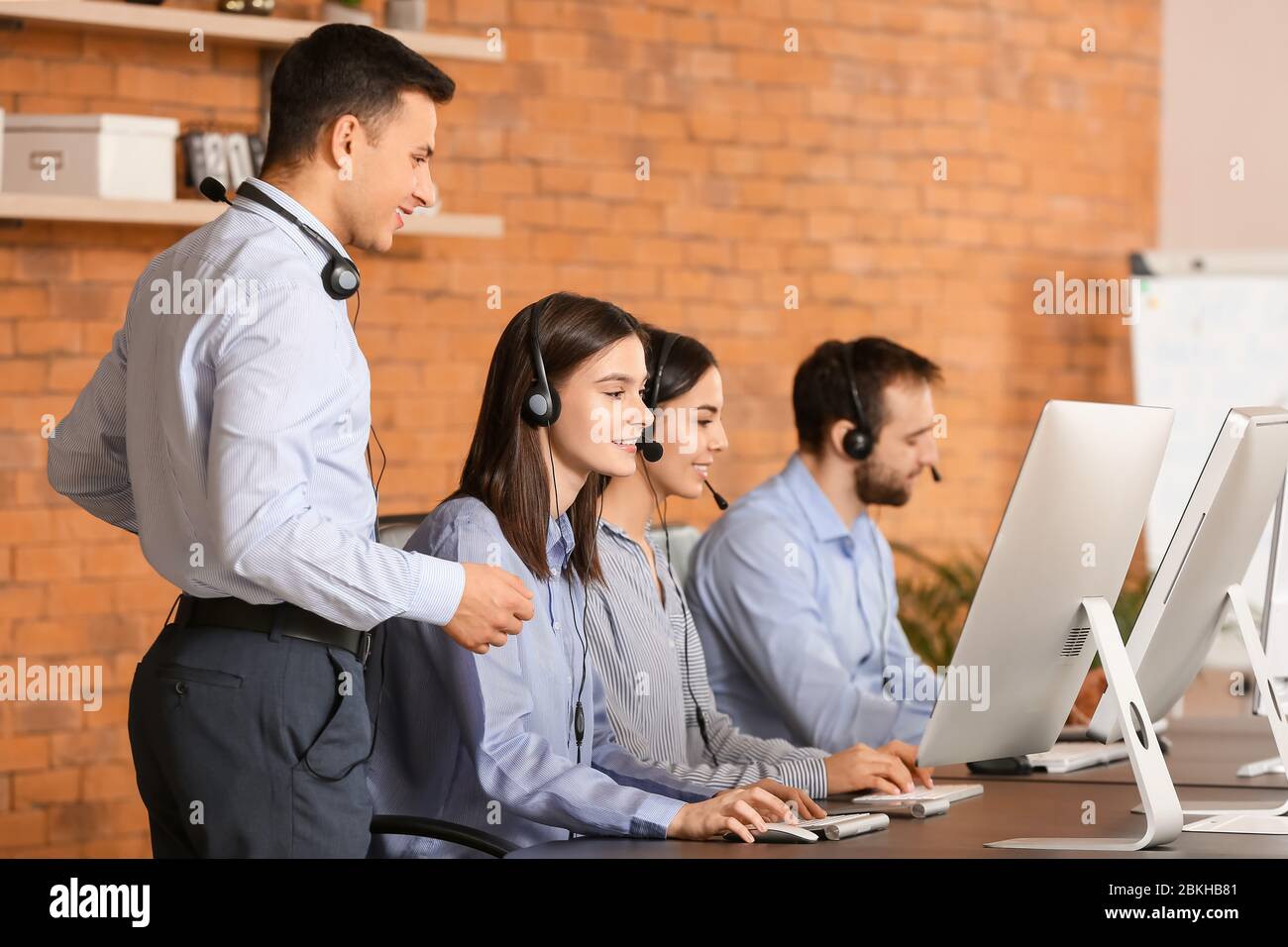 Professional technical support agent teaching young people in office ...
