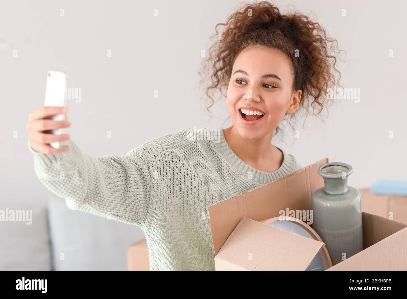Young woman with moving box taking photo in her new home Stock Photo ...