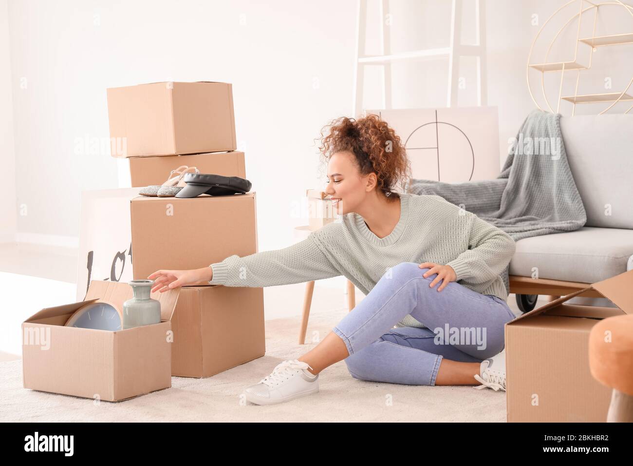 Young woman unpacking moving boxes in her new home Stock Photo - Alamy