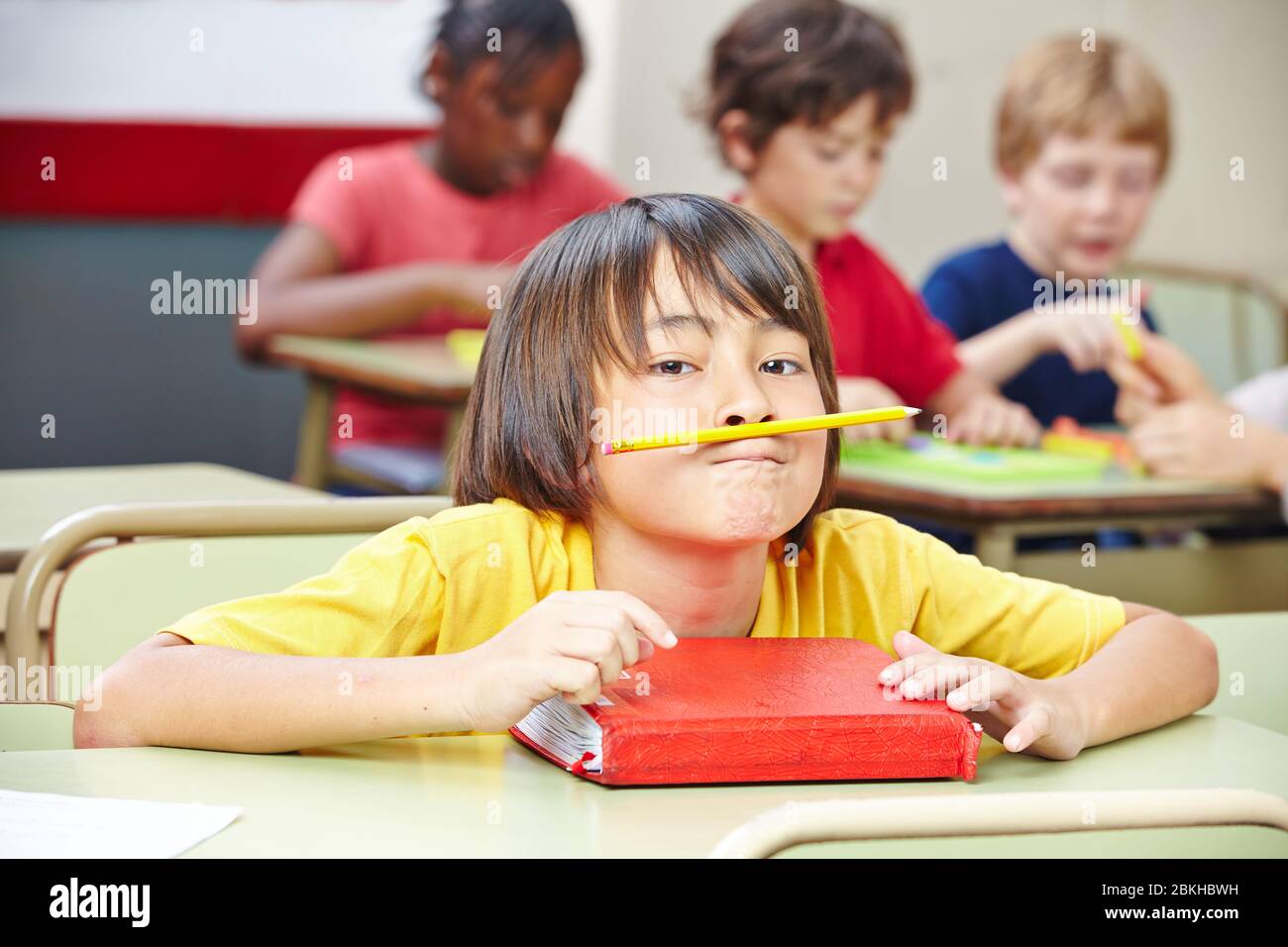 Child balances pen with lips in class in elementary school Stock Photo ...