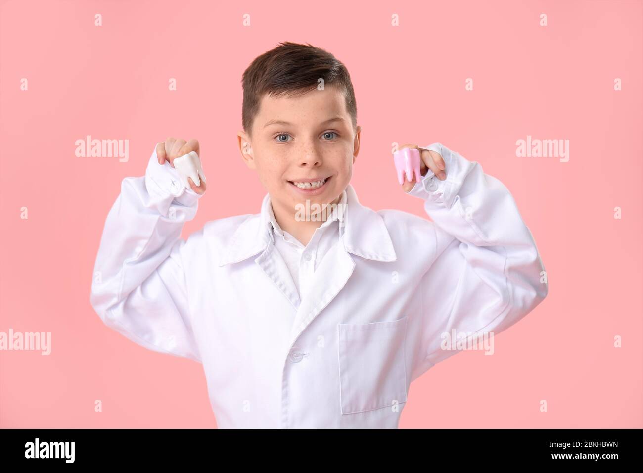 Little dentist with models of teeth on color background Stock Photo - Alamy