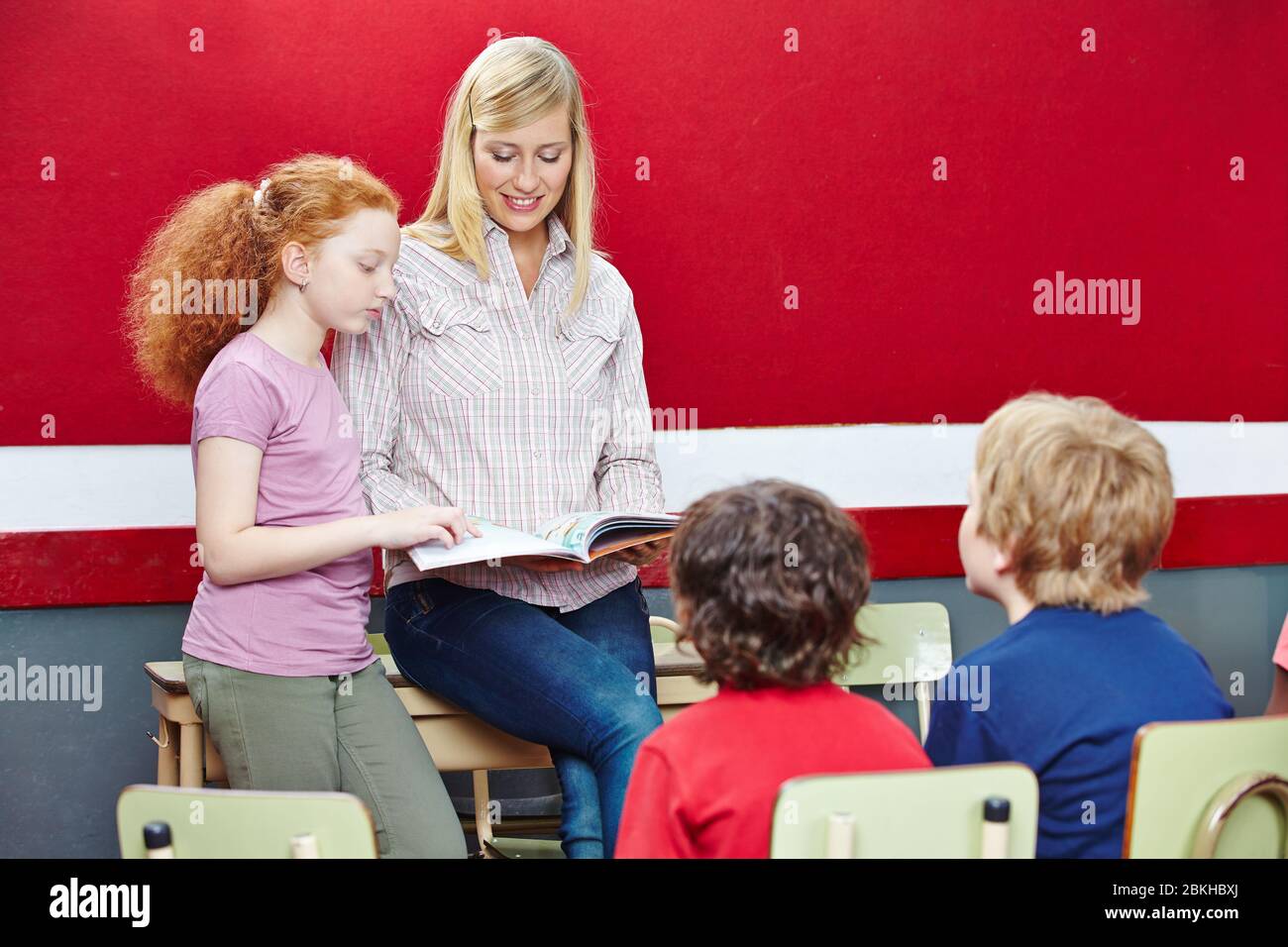 Teacher reads from a textbook in primary school Stock Photo - Alamy