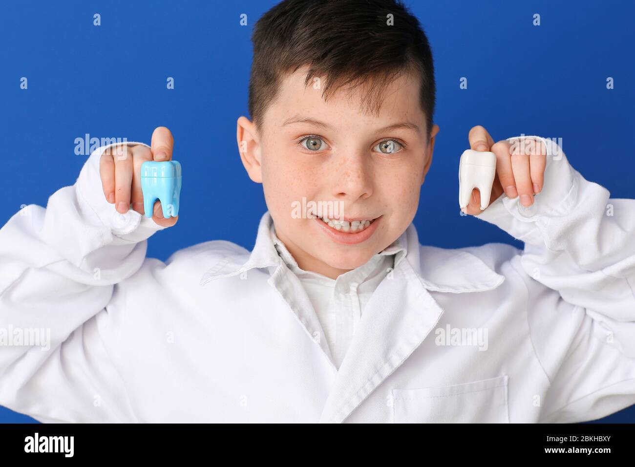 Little dentist with models of teeth on color background Stock Photo - Alamy