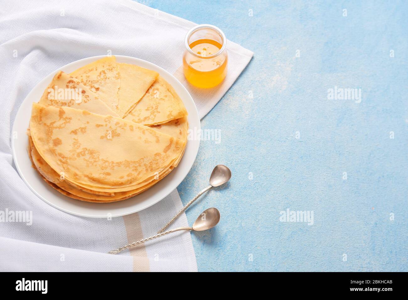 Tasty blini with honey on color background Stock Photo - Alamy