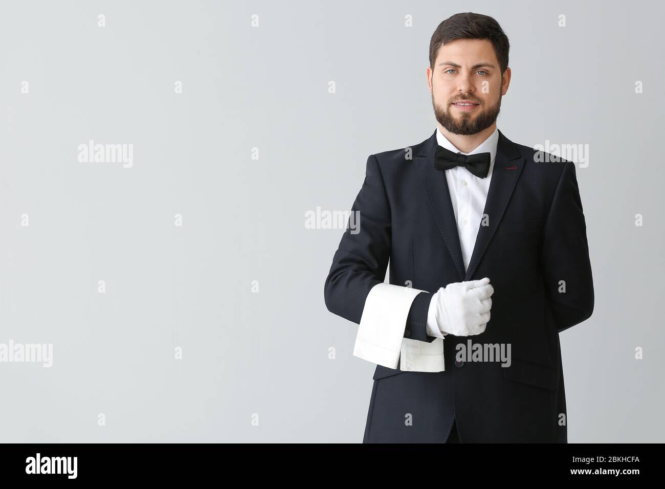 Handsome male waiter on grey background Stock Photo - Alamy