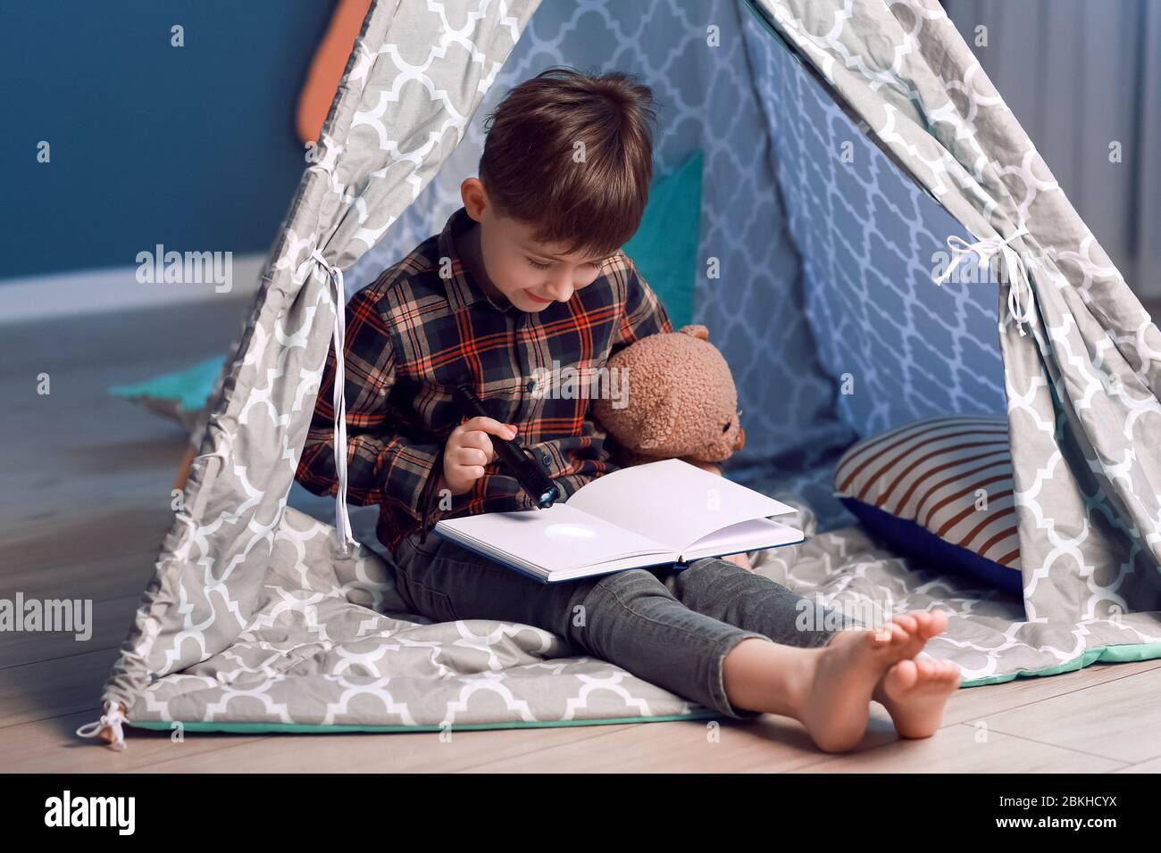 Little boy reading book in play tent at night Stock Photo - Alamy