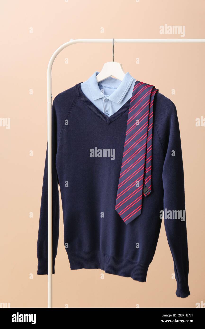 Stylish school uniform hanging on rack against color background Stock ...