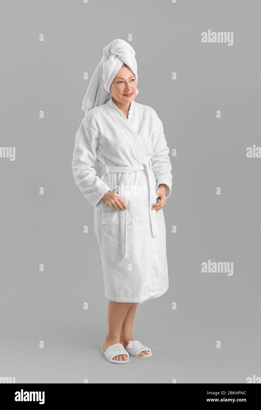 Mature woman in bathrobe on grey background Stock Photo - Alamy