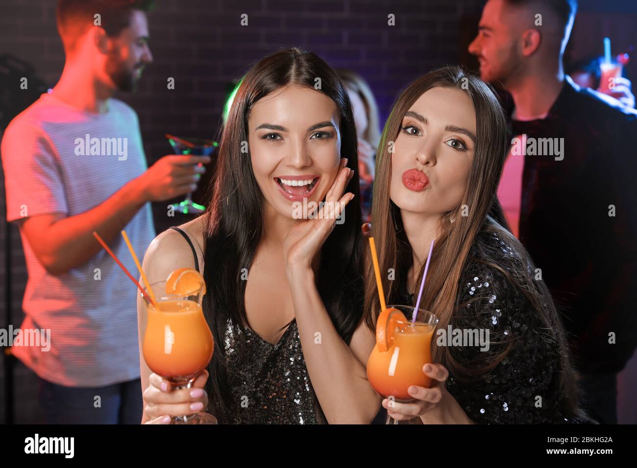 Happy young women with cocktails in night club Stock Photo - Alamy