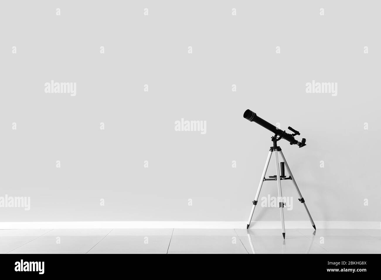 Modern telescope near light wall Stock Photo - Alamy