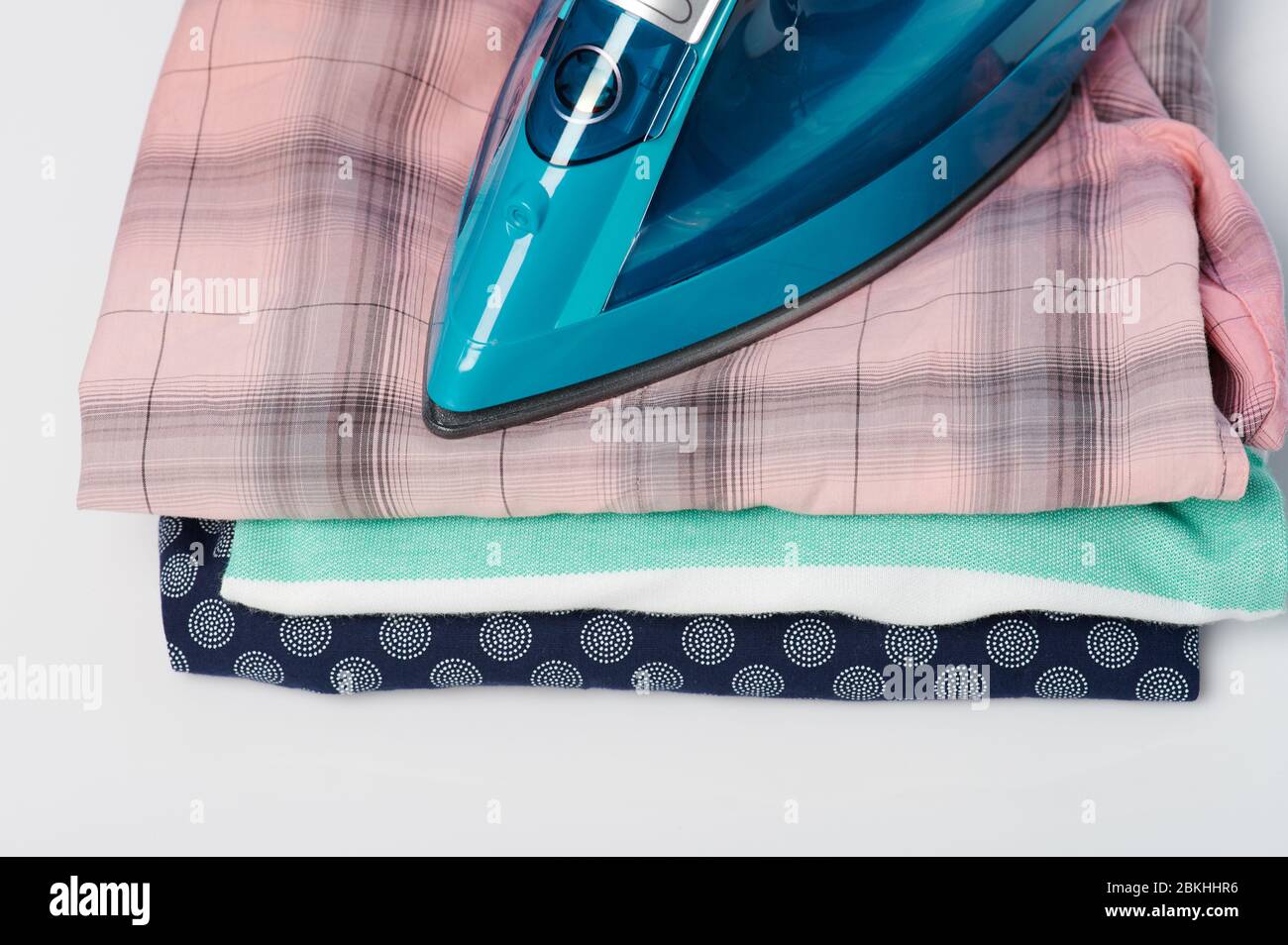 Modern iron on stack of cloth isolated on white background Stock Photo ...