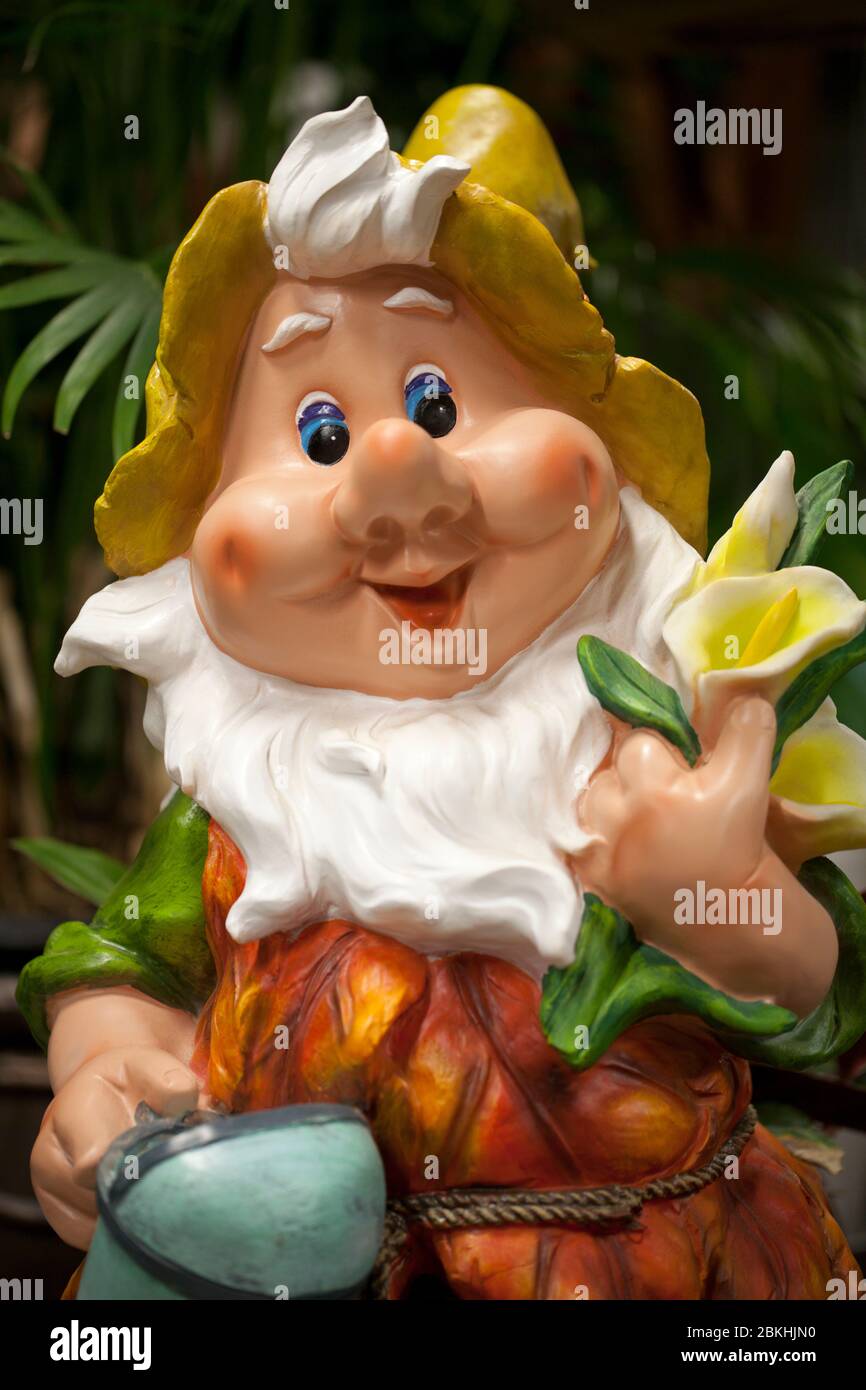 Cute dwarf living in a garden. Smiling garden gnome decoration against ...