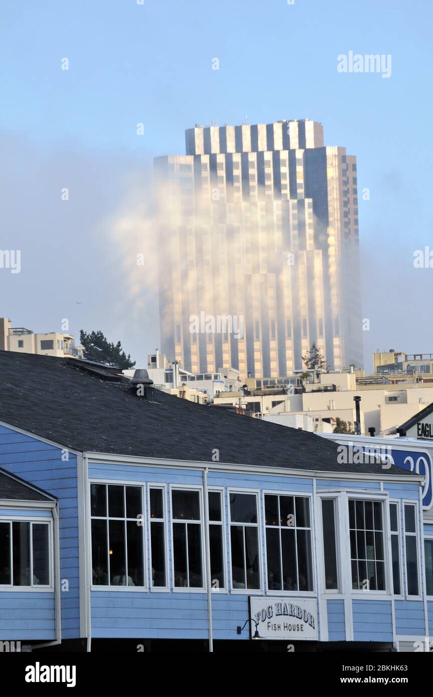 Evening light illuminates a bank of fog over Pier 39, Fishermans Wharf ...