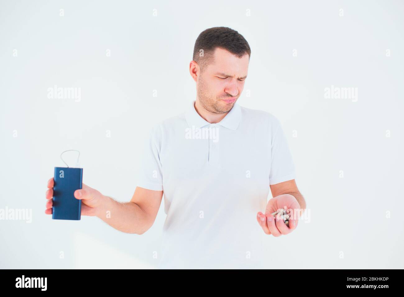 Young man isolated over white background. Unhappy guy hold batteries ...