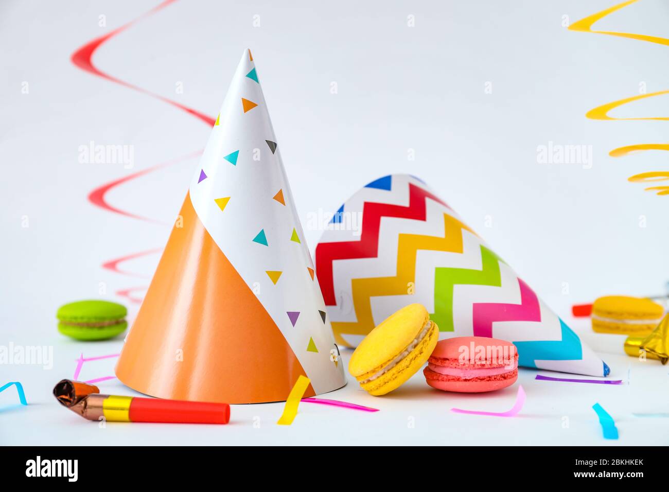 Party hats, decor and macarons on light background Stock Photo - Alamy