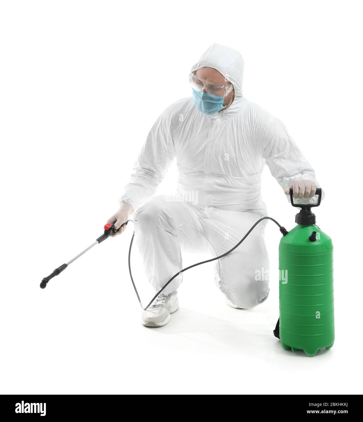 Worker in biohazard suit and with disinfectant on white background ...