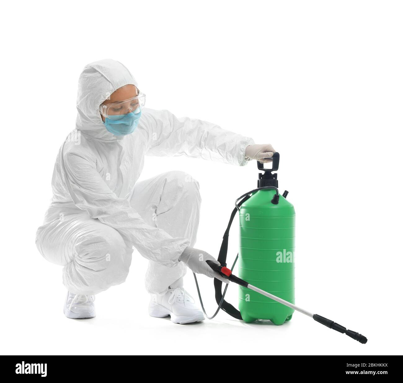 Worker in biohazard suit and with disinfectant on white background ...