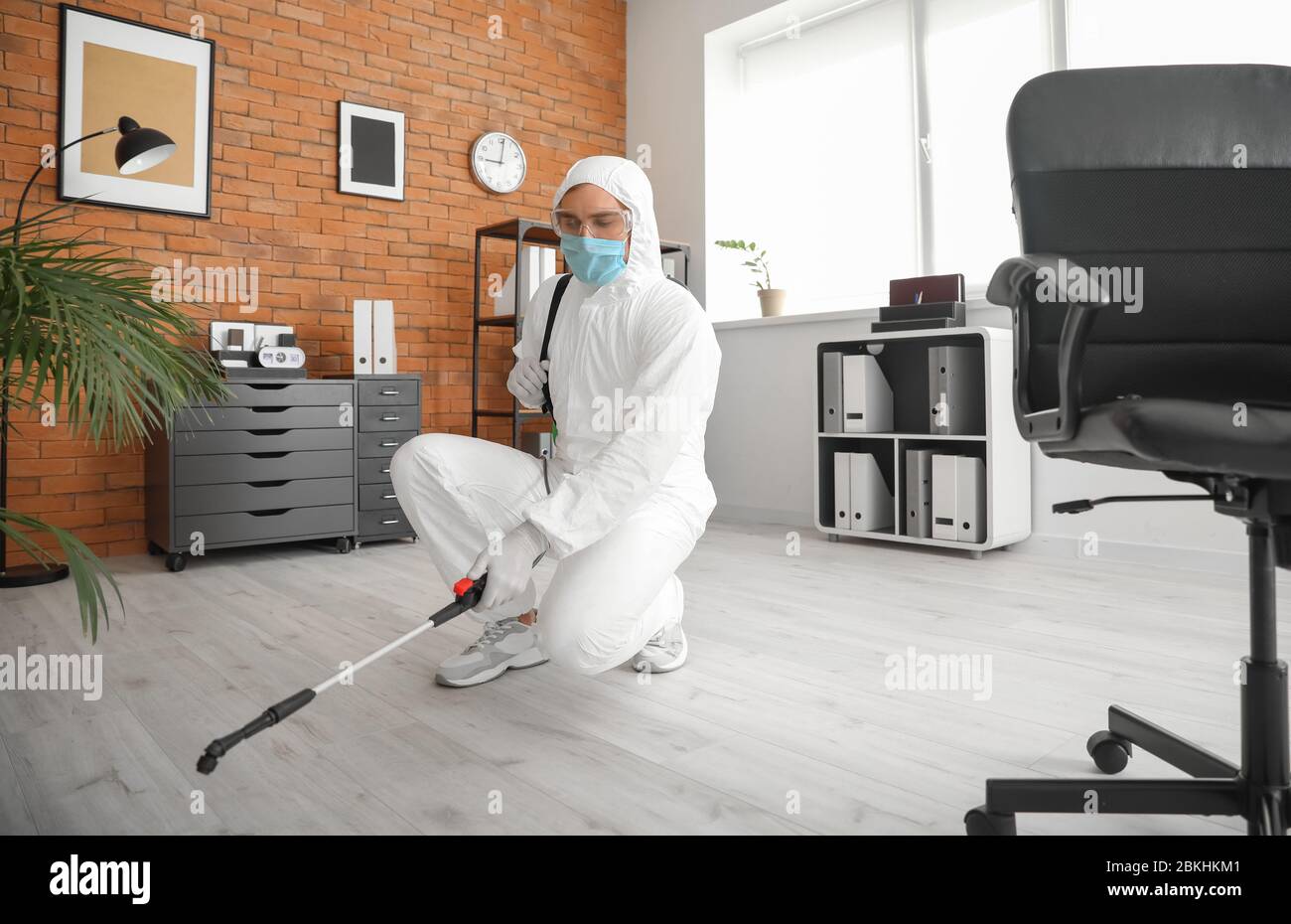 Worker in biohazard suit disinfecting office Stock Photo - Alamy