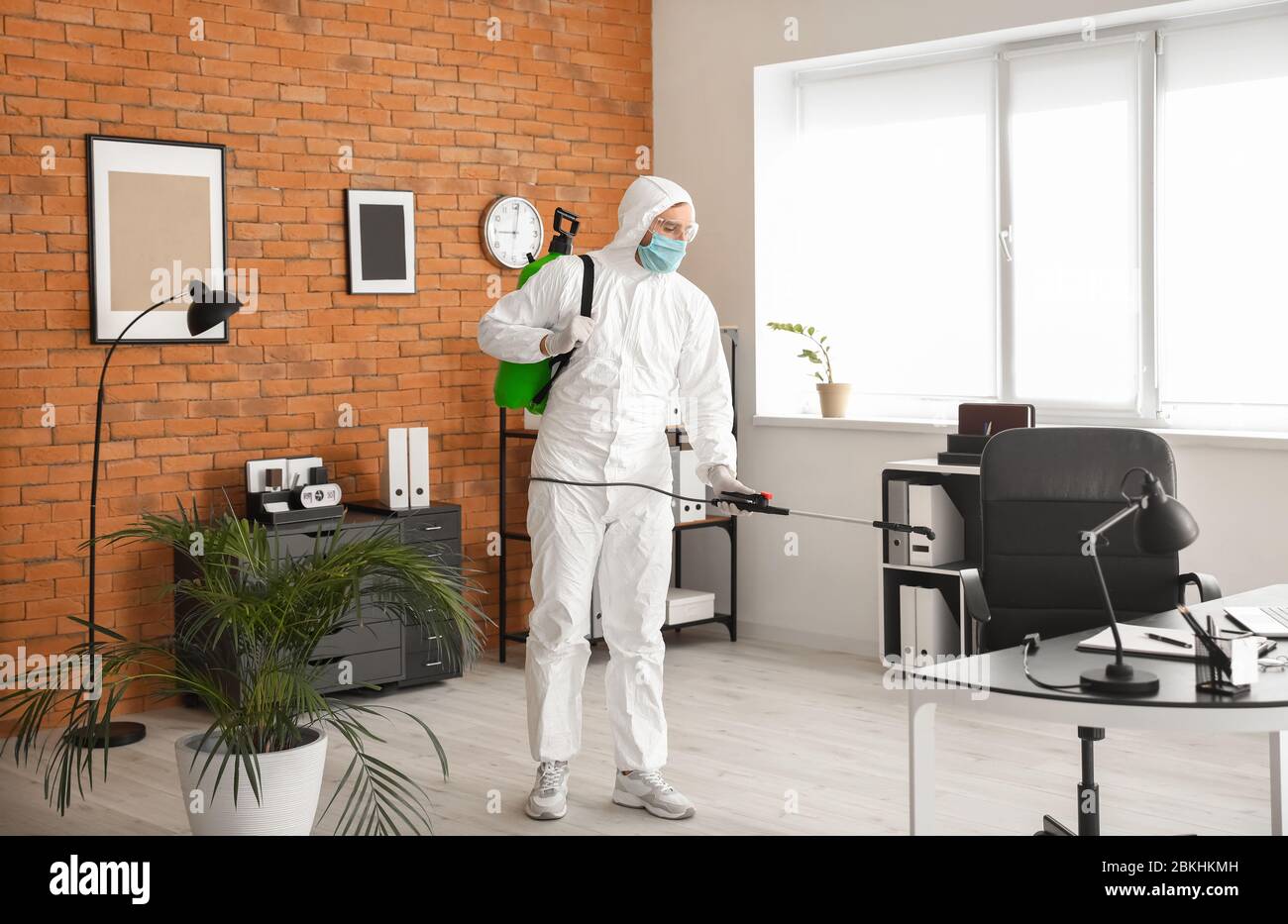 Worker in biohazard suit disinfecting office Stock Photo - Alamy
