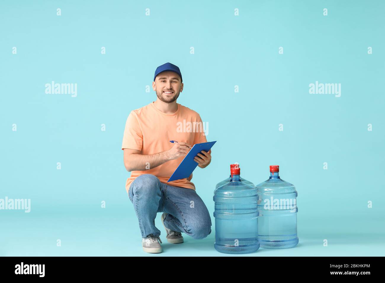 Delivery man with bottles of water on color background Stock Photo - Alamy