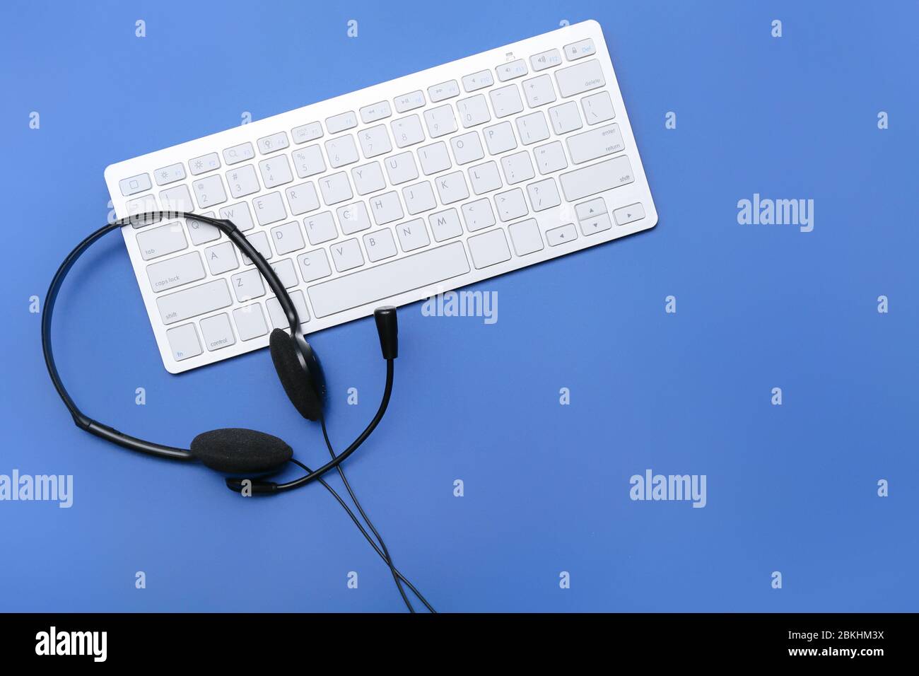PC keyboard with headset on color background Stock Photo - Alamy