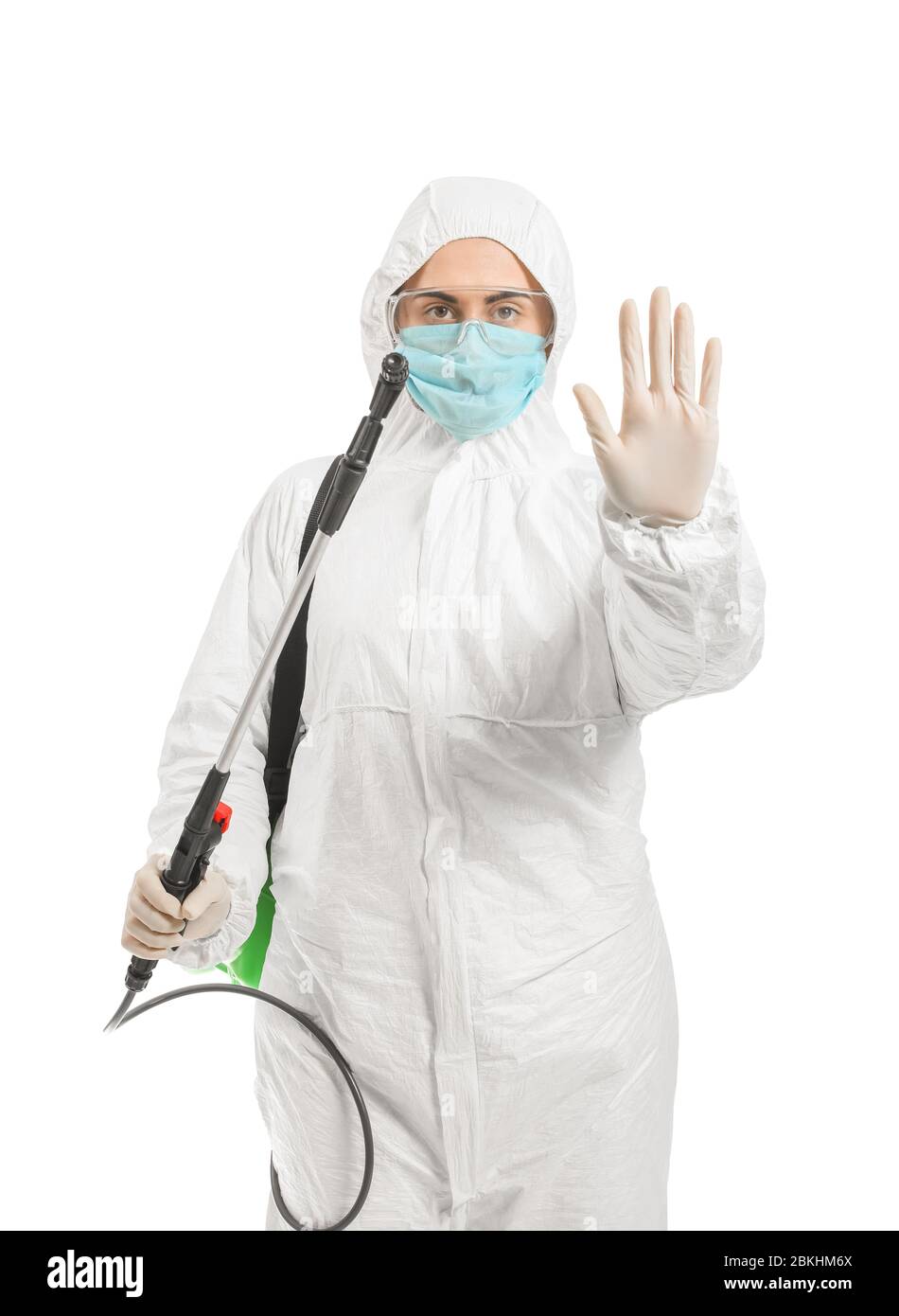 Worker in biohazard suit and with disinfectant showing stop gesture on ...