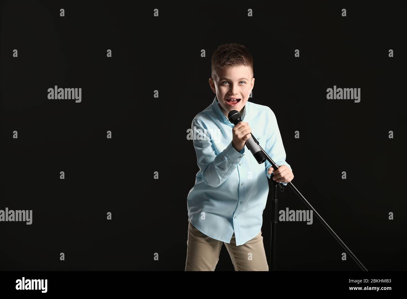 Cute little boy singing against dark background Stock Photo - Alamy
