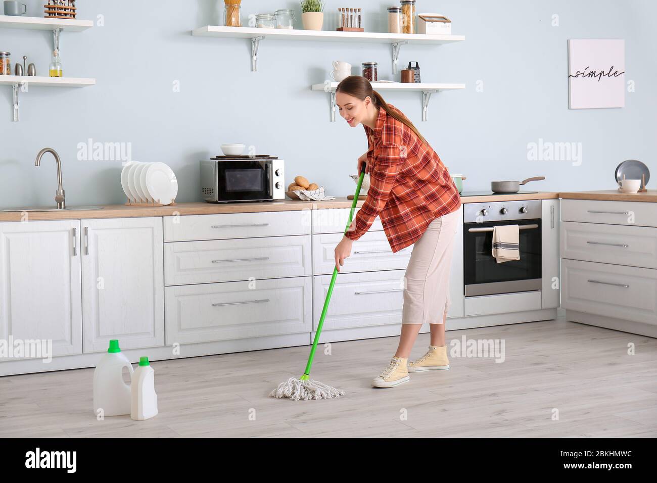 Young woman mopping floor in kitchen Stock Photo - Alamy