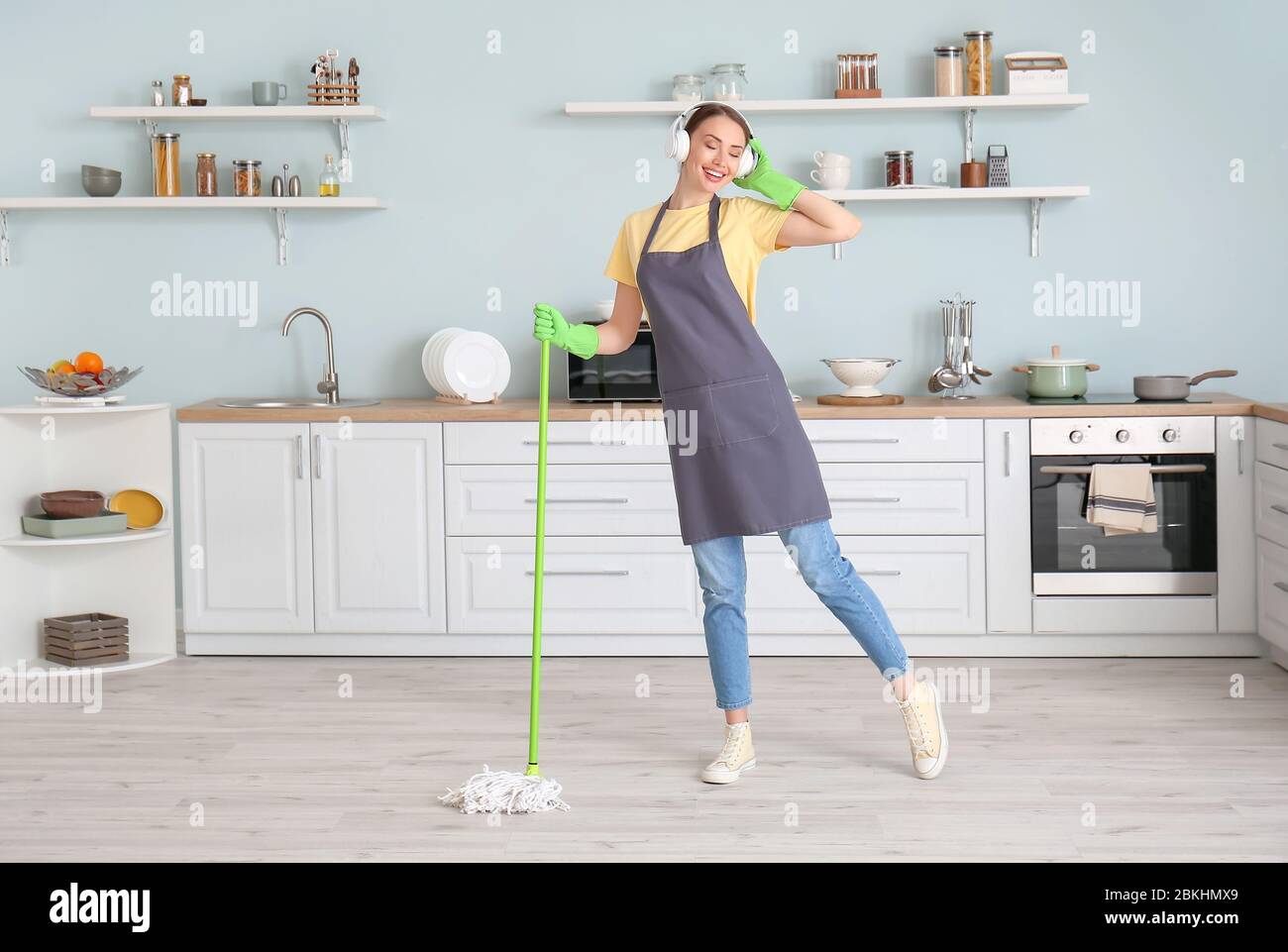 Young woman having fun while mopping floor in kitchen Stock Photo - Alamy