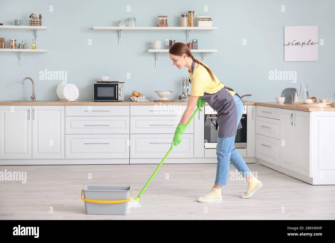 Young woman mopping floor in kitchen Stock Photo - Alamy