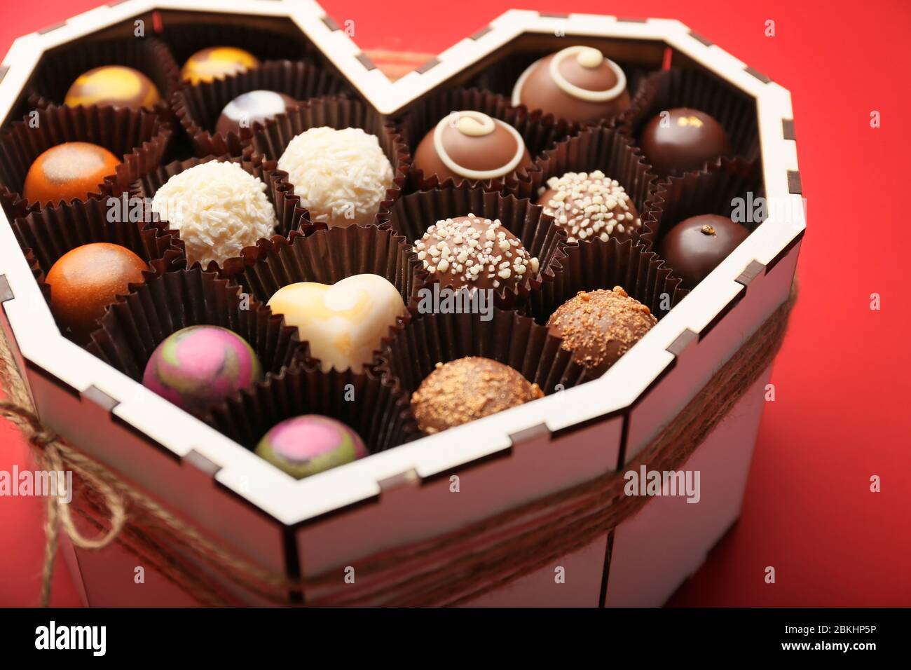 Heart-shaped box with chocolate candies on color background Stock Photo ...