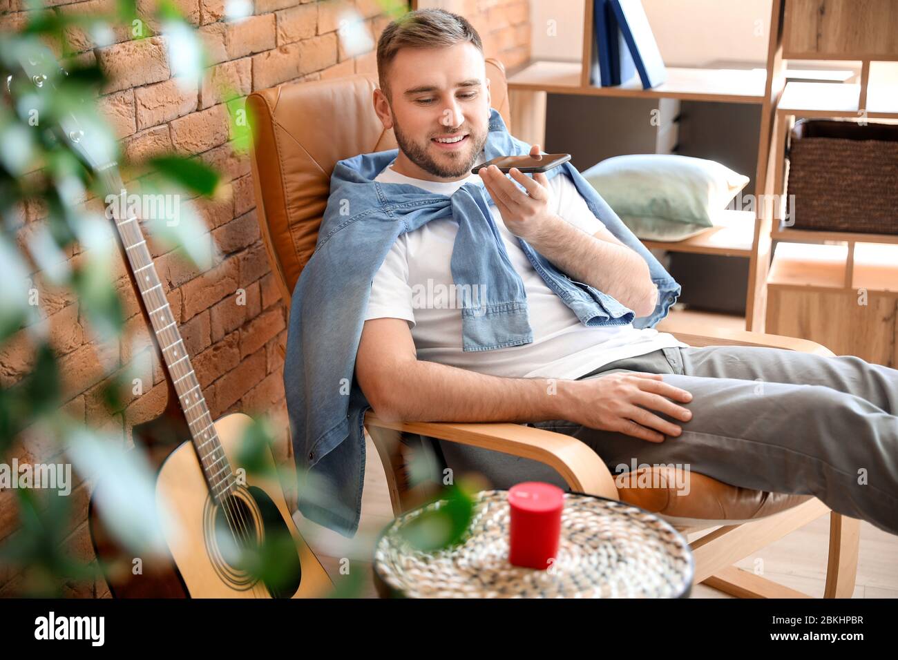 Young man with smart home assistant device in room Stock Photo - Alamy