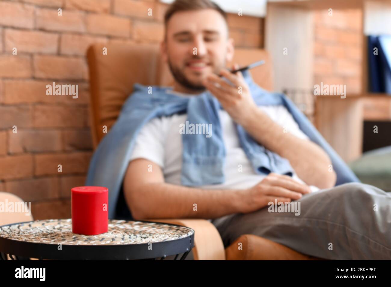 Young man with smart home assistant device in room Stock Photo - Alamy