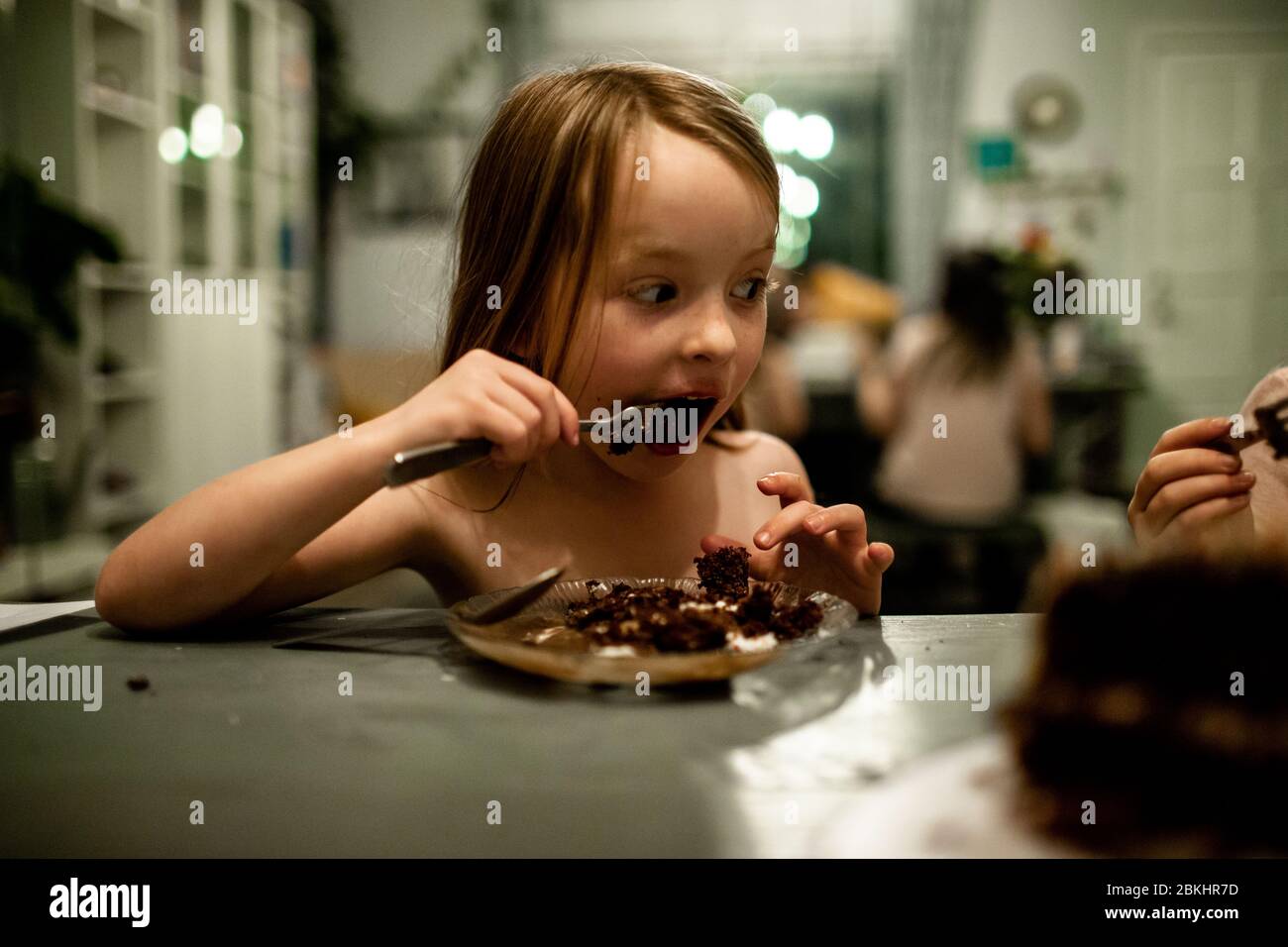 young girl with surprised face while eating cake Stock Photo - Alamy