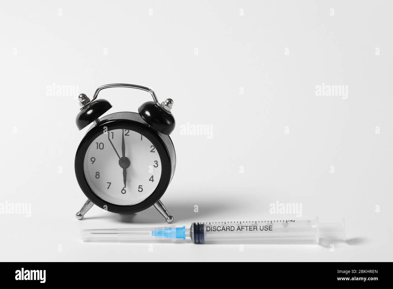 Take medicine on time. syringe and alarm clock on white background ...