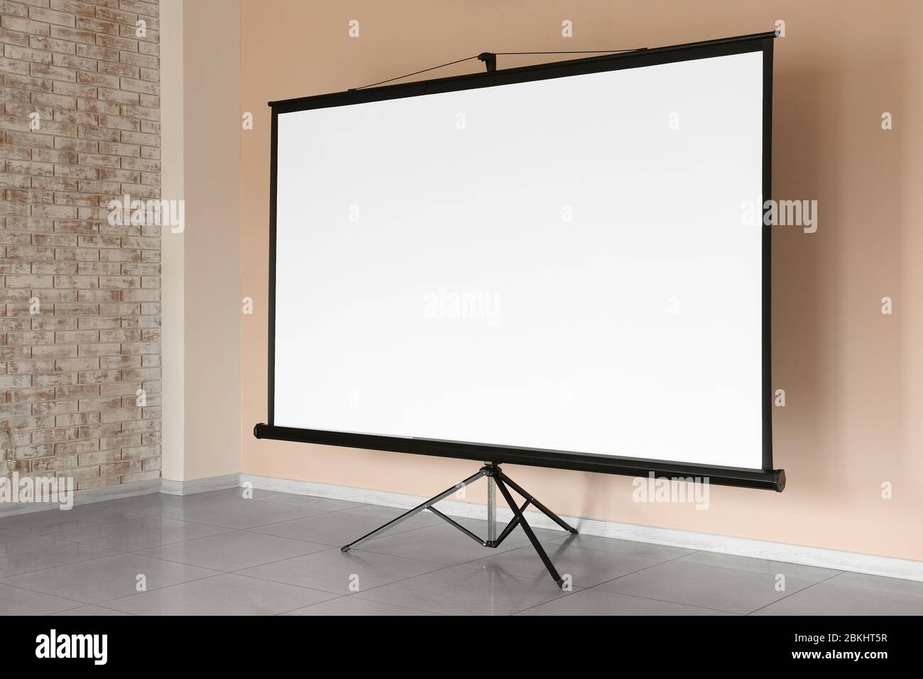Modern projector screen near wall indoors Stock Photo - Alamy
