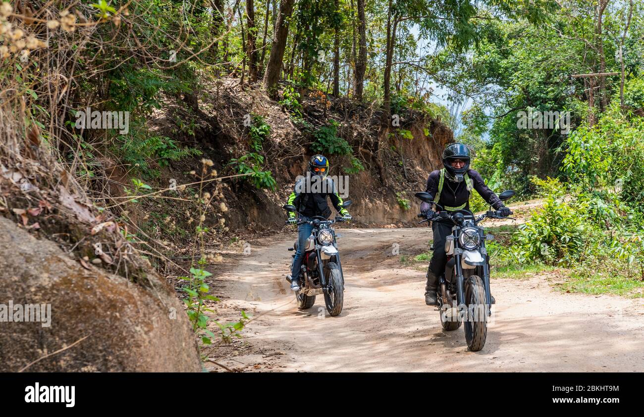 two friends riding their scrambler motorcycles through forrest Stock ...