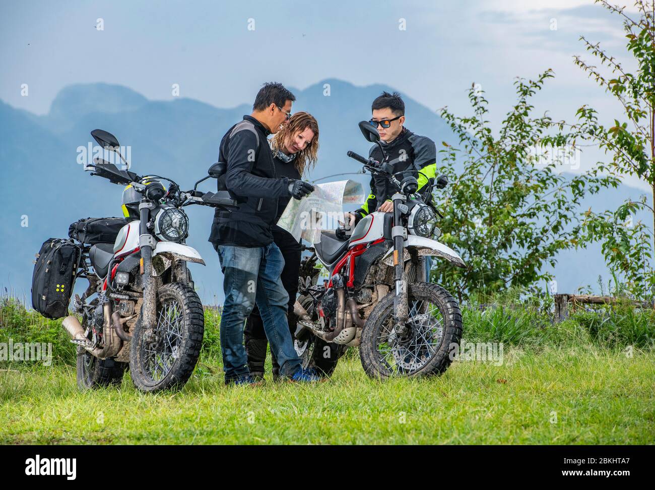 three friends looking at map on motorcycle trip Stock Photo - Alamy