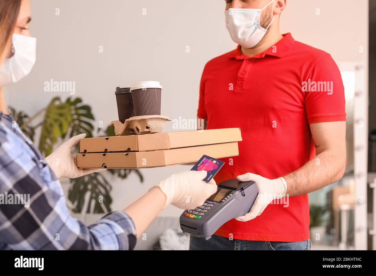 Woman paying courier of food delivery company for order via terminal ...