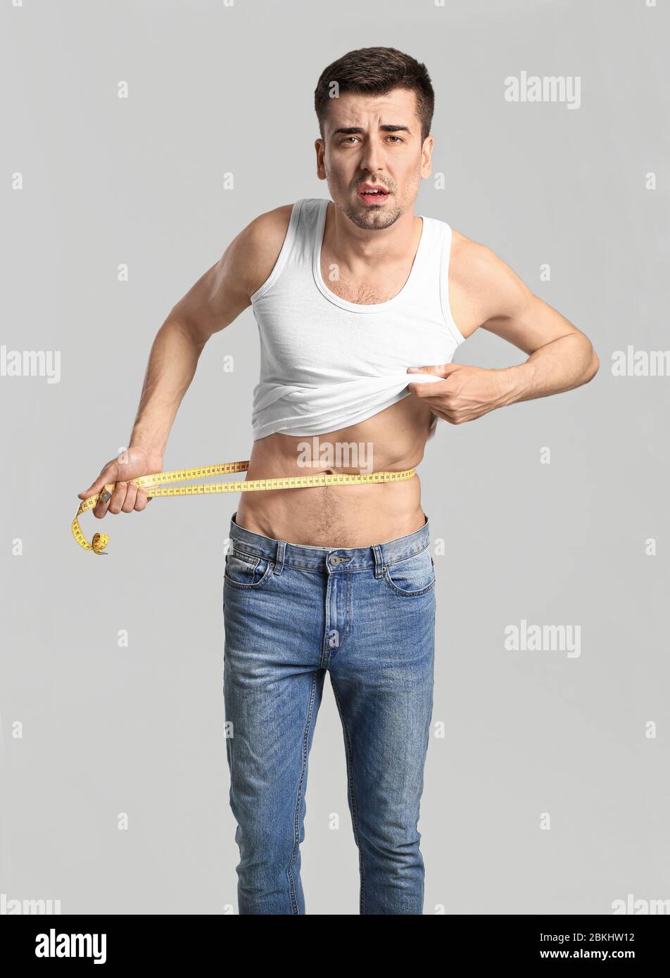 Sick man measuring his waist on grey background. Concept of anorexia ...