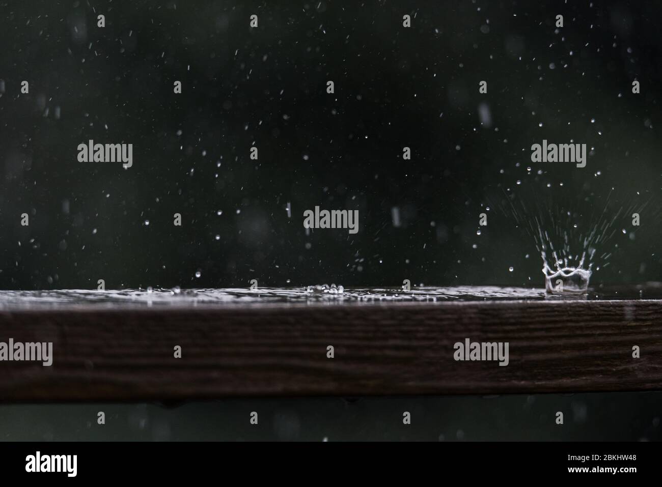 Close up of raindrops hitting a wooden railing with a splash Stock ...