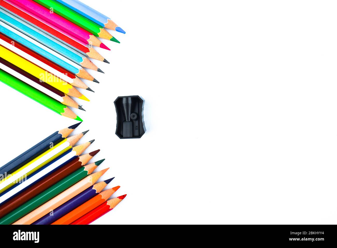 Different colored wood pencil crayons pointing at a black color plastic ...