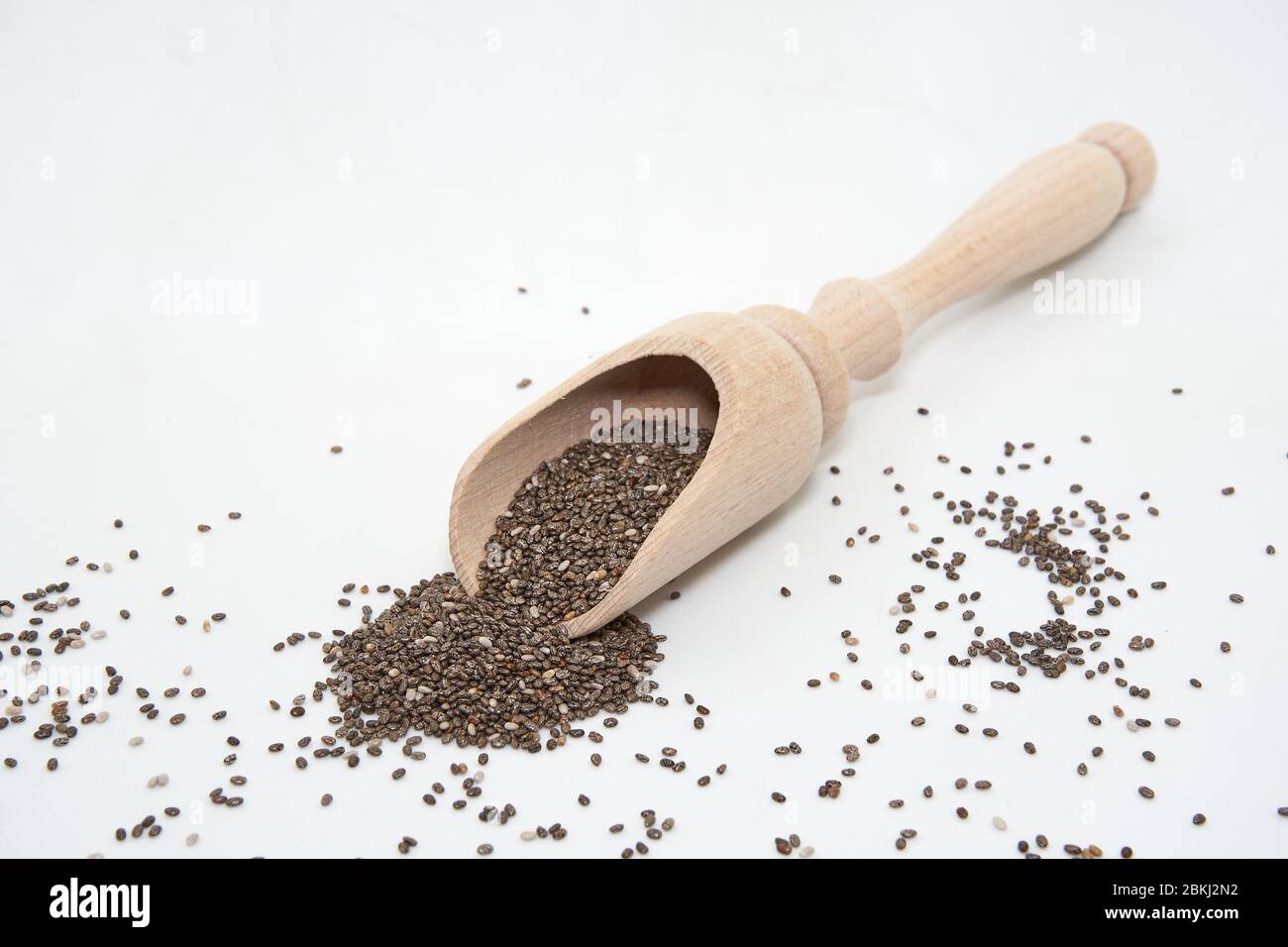 on a white surface, spilling a large amount of chia seeds. The small ...
