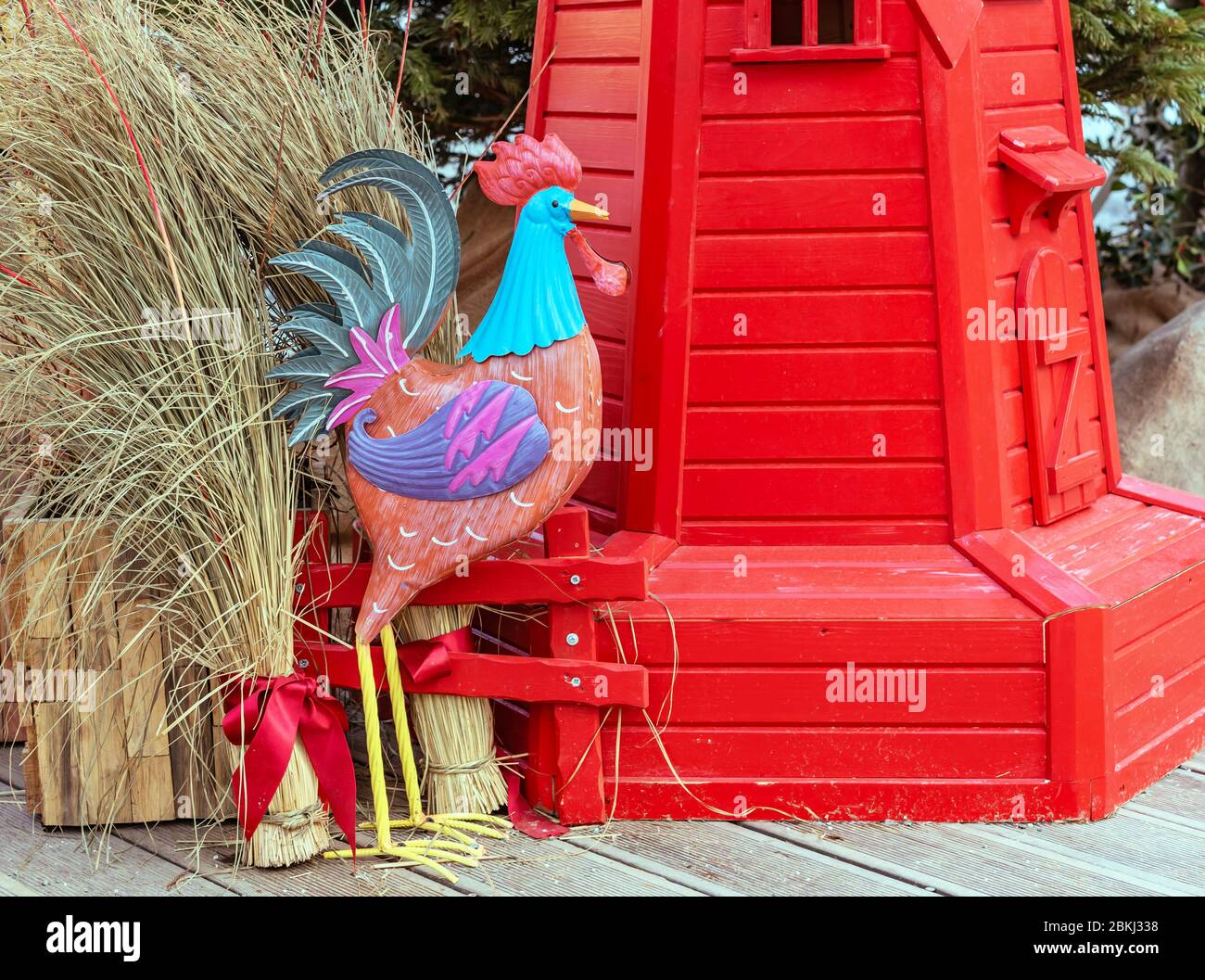 Colorful metal figure of a rooster on a background of a red mill Stock ...